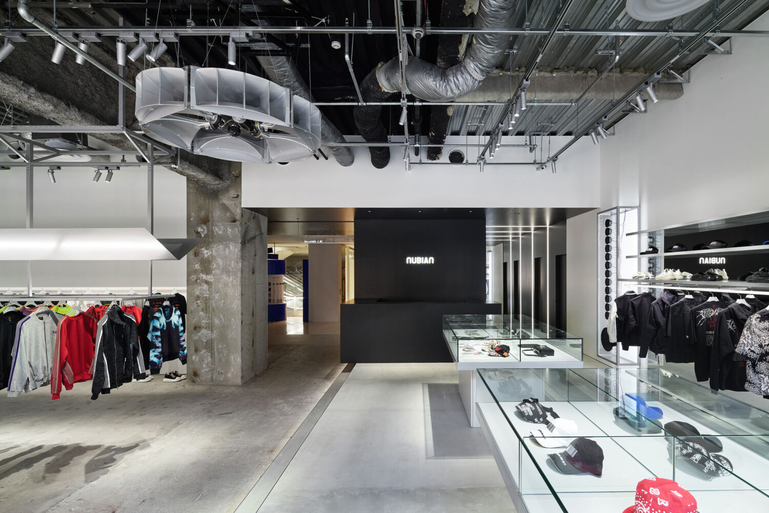 トラフによる、名古屋市の店舗「NUBIAN NAGOYA PARCO」。商業施設の内と外に入口がある区画に計画。環境条件の空間演出への援用を目指し、内では視界を絞り入店体験を設計して外では高低 ...