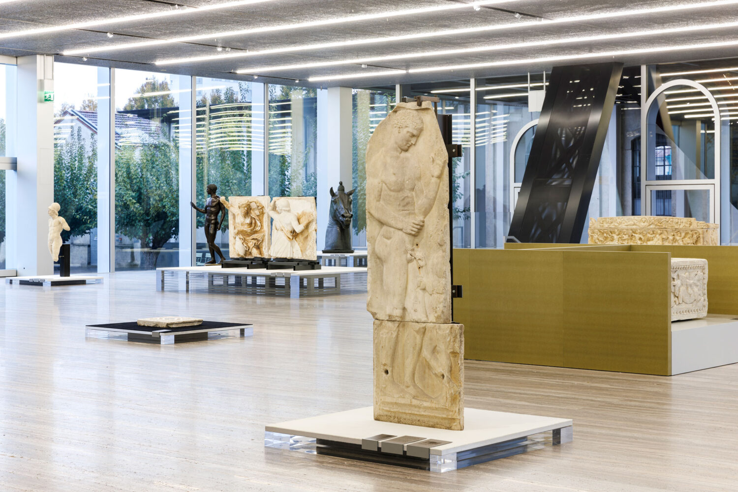 レム・コールハース / OMAの会場構成による、イタリアのプラダ財団での展覧会「リサイクリング・ビューティー」。中世からバロック時代での古代遺産の再利用に注目。アクリル製台座やオフィスチェアを ...